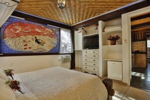 Quarto com cama, televisão, penteadeira e um quadro na parede.