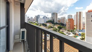 Varanda com vista para a cidade, ar condicionado e grade de metal.