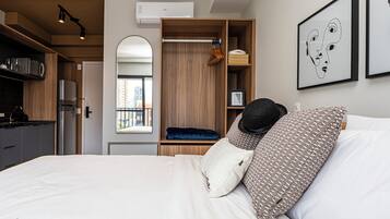 Quarto com cama, guarda-roupa, espelho e uma kitchenette.