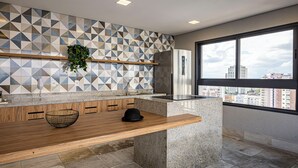 Uma cozinha moderna com um painel geométrico, uma janela ampla com vista para a cidade e bancada de madeira.