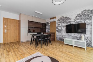 Cozinha moderna com área de jantar, televisão de tela plana na parede e piso de madeira.
