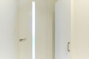 Uma porta fechada com maçaneta simples e interruptor de luz na parede.