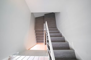 Uma escadaria moderna com corrimão branco e degraus de madeira.