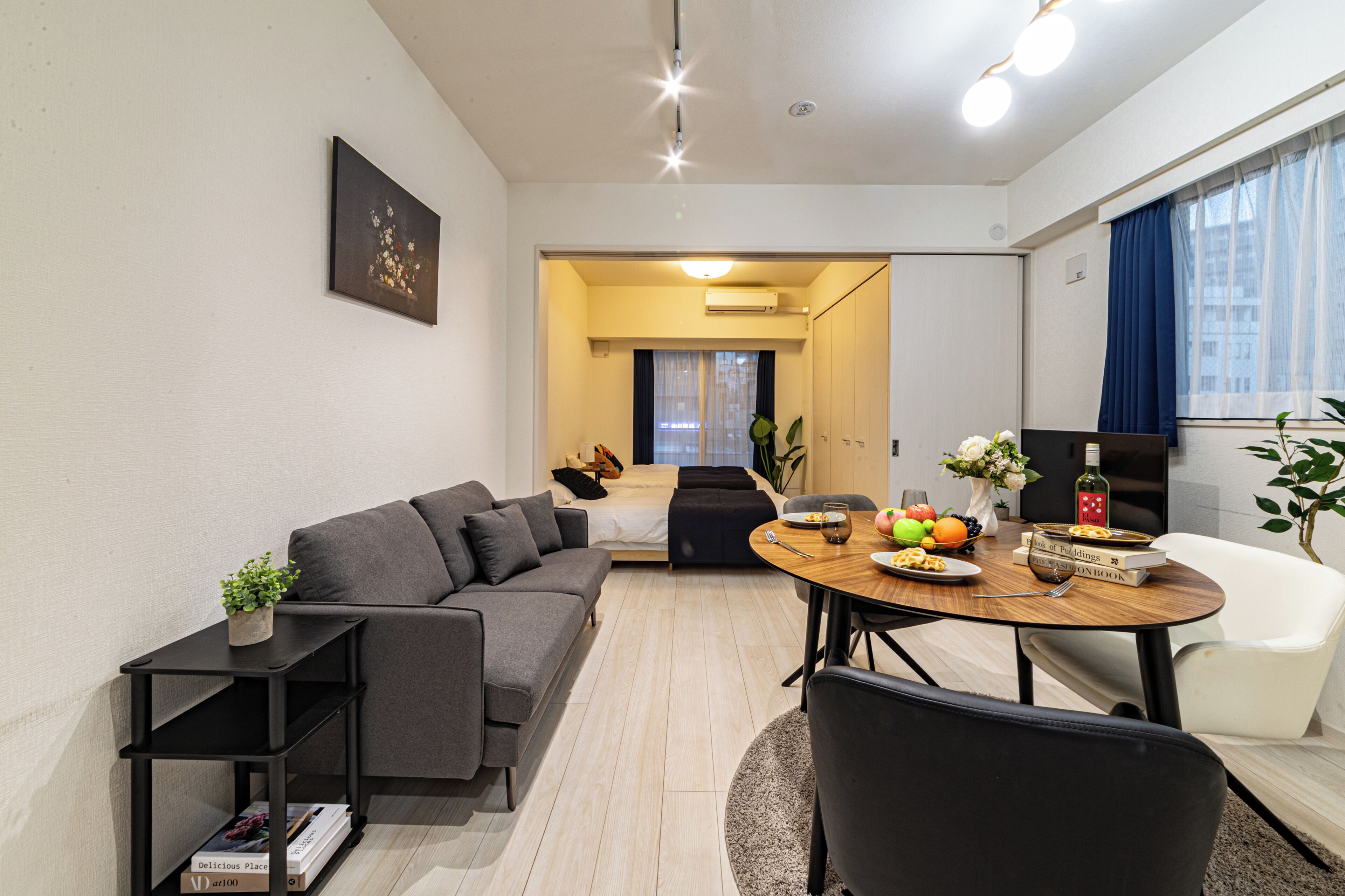 Uma sala de estar moderna com um sofá, uma mesa de jantar com um vaso de flores e uma televisão.