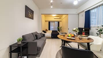 Uma sala de estar moderna com um sofá, uma mesa de jantar com um vaso de flores e uma televisão.