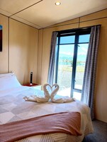 Quarto de hotel com cama, mesa de cabeceira e janela com cortinas.