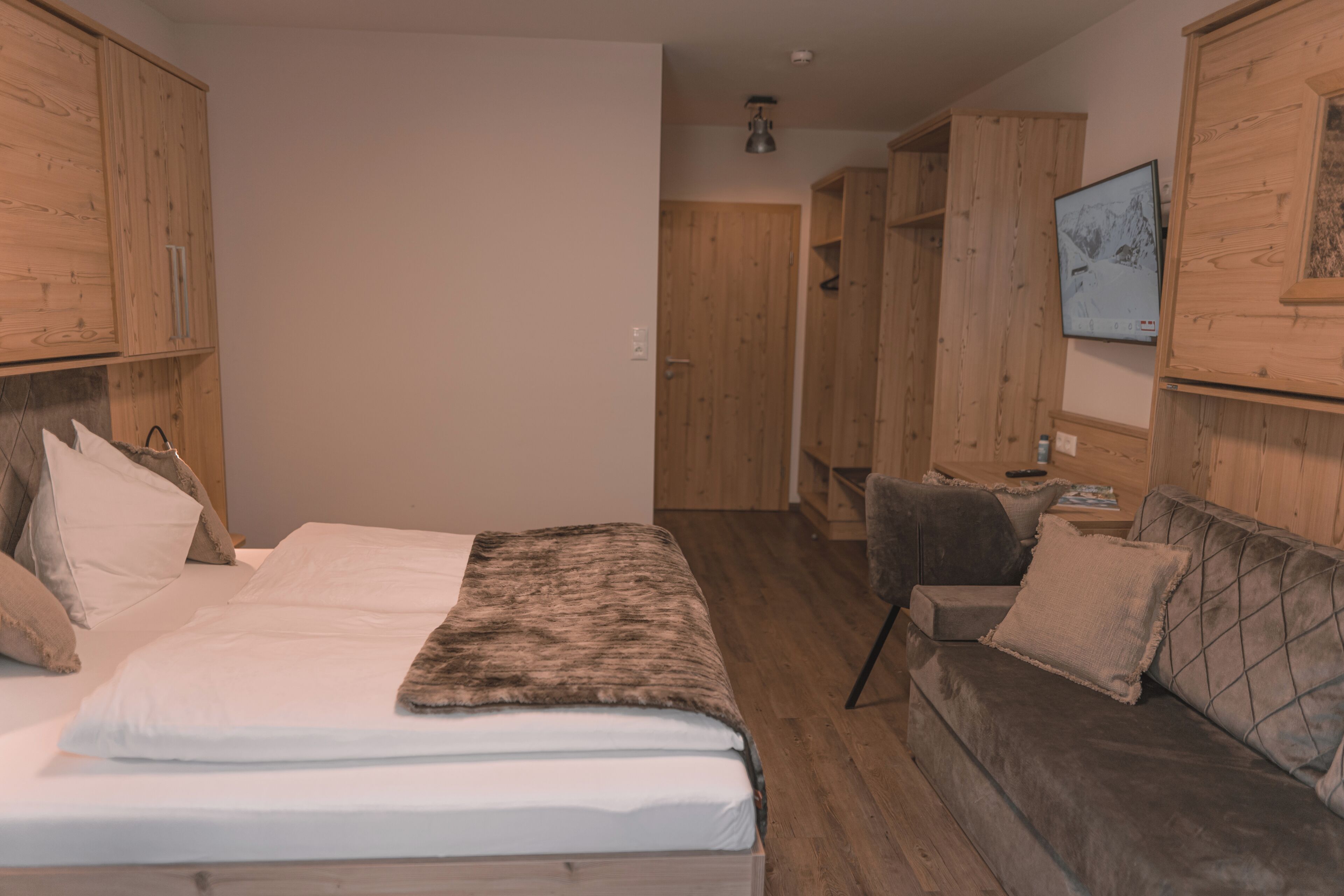 Quarto com cama, sofá, armários de madeira e uma imagem pendurada.