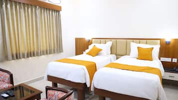 Quarto de hotel com duas camas, uma mesinha e uma cadeira.