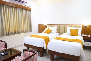 Quarto de hotel com duas camas, uma mesinha e uma cadeira.