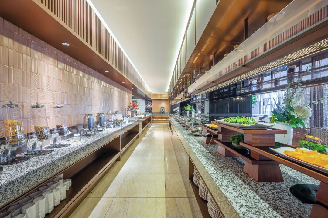 Cozinha de hotel moderna, com bancadas de granito, eletrodomésticos de aço inoxidável e um balcão de serviço extenso.