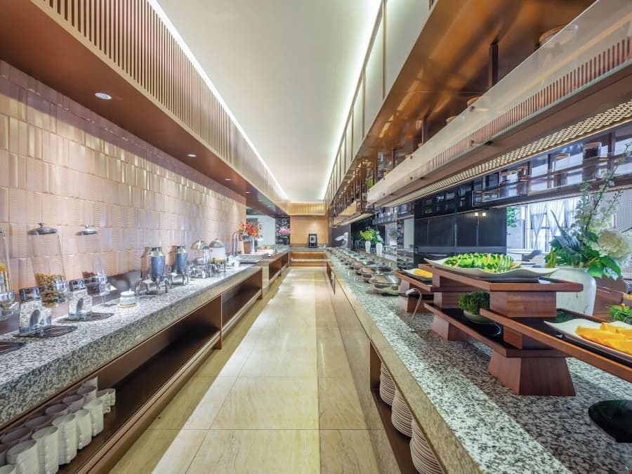 Cozinha de hotel moderna, com bancadas de granito, eletrodomésticos de aço inoxidável e um balcão de serviço extenso.