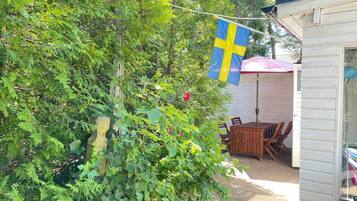 Um jardim com uma bandeira sueca, uma mesa de madeira e cadeiras.