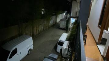 Uma área de estacionamento com duas carrinhas brancas, uma estrutura de metal e um edifício com varanda.