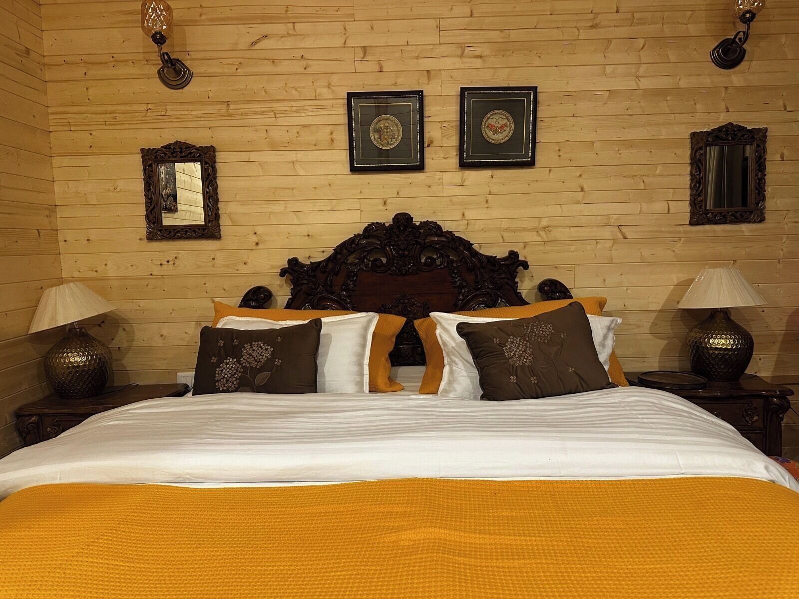 Quarto com painéis de madeira, uma cama grande, duas fotos emolduradas na parede e duas luminárias de cada lado da cama.