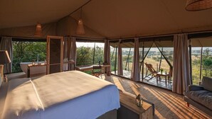 Quarto espaçoso com uma cama grande, uma escrivaninha e uma cadeira, tudo com vista para o exterior.