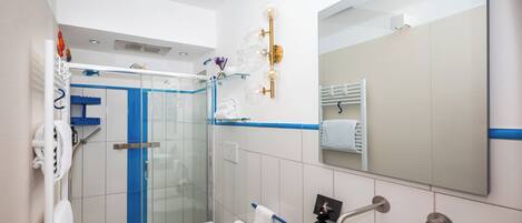 Um banheiro moderno com box de vidro, vaso sanitário branco, pia com espelho e porta-toalhas.