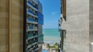 Um edifício alto com vista para o oceano e a praia.