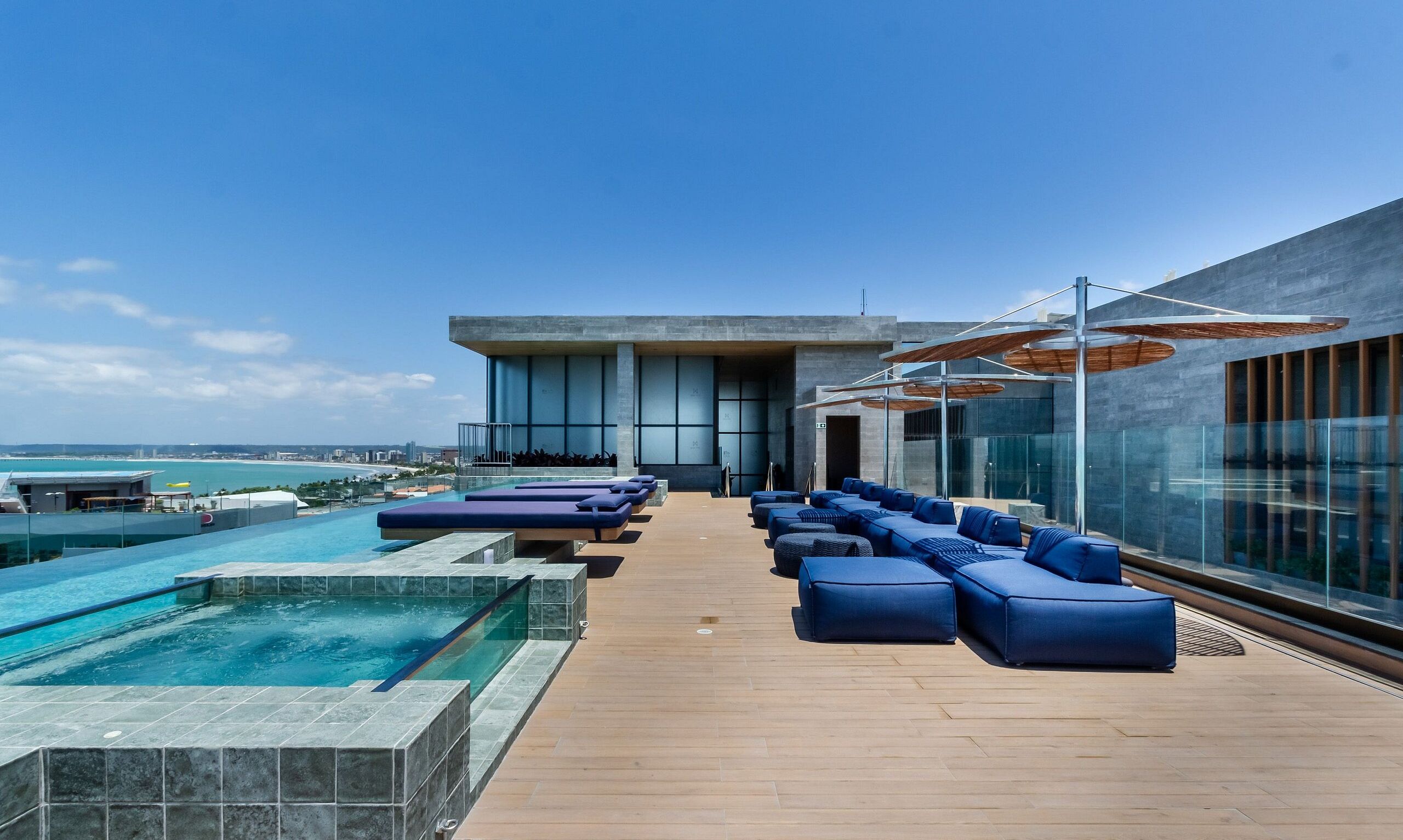 Uma área de piscina no terraço, com espreguiçadeiras e vista para o oceano.