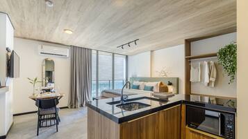 Quarto de hotel moderno com cozinha, mesa de jantar e uma janela grande.