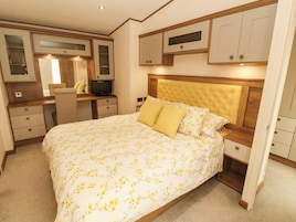 Quarto com uma cama grande, escrivaninha, cadeira, televisão e armários embutidos.