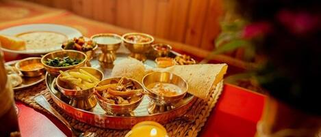 Uma refeição tradicional indiana com diversos pratos e utensílios sobre um tapete tecido.