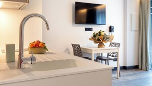 Uma cozinha moderna com uma pia grande, uma TV de tela plana na parede e um espaço de jantar com mesa e cadeiras.