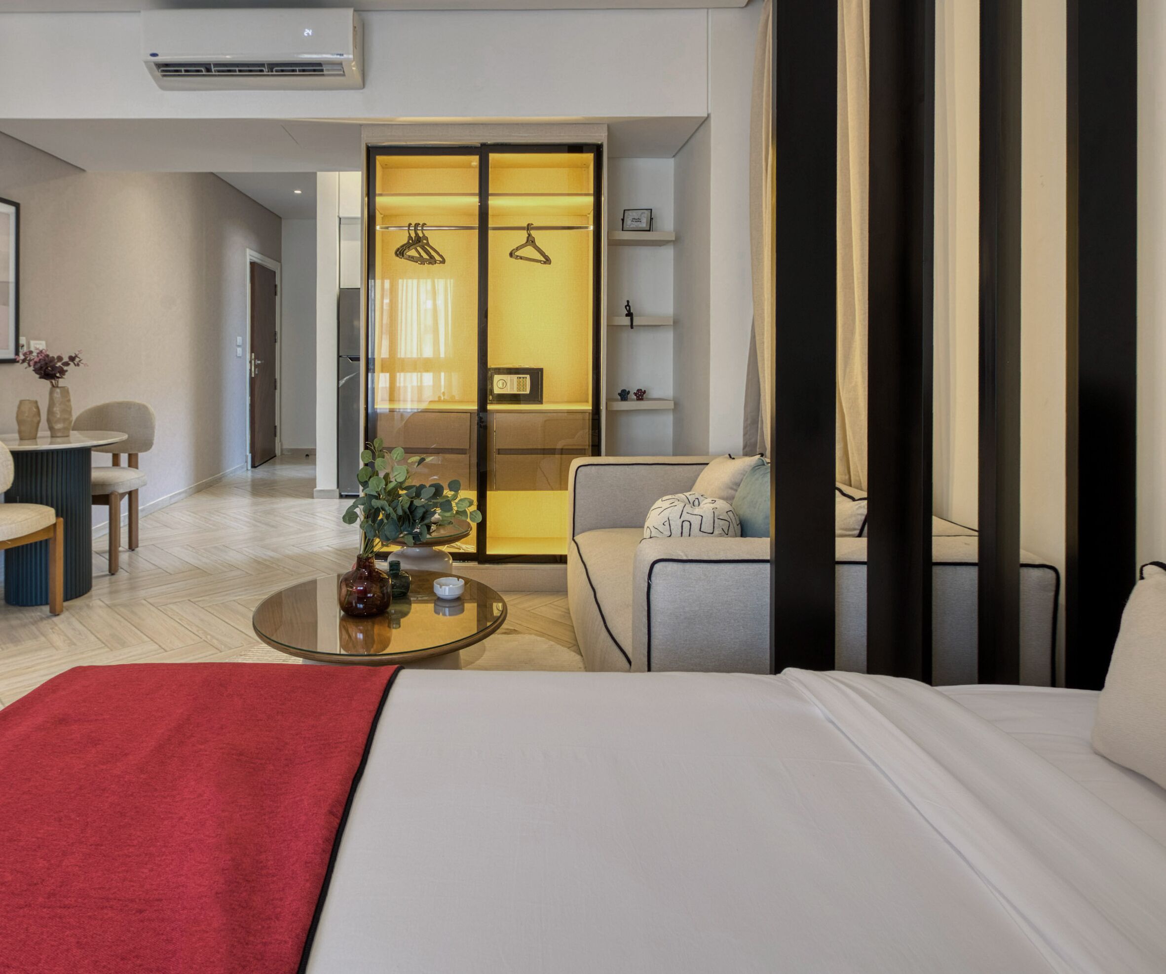 Quarto de hotel moderno com cama, área de estar com mesa e porta deslizante para um banheiro.