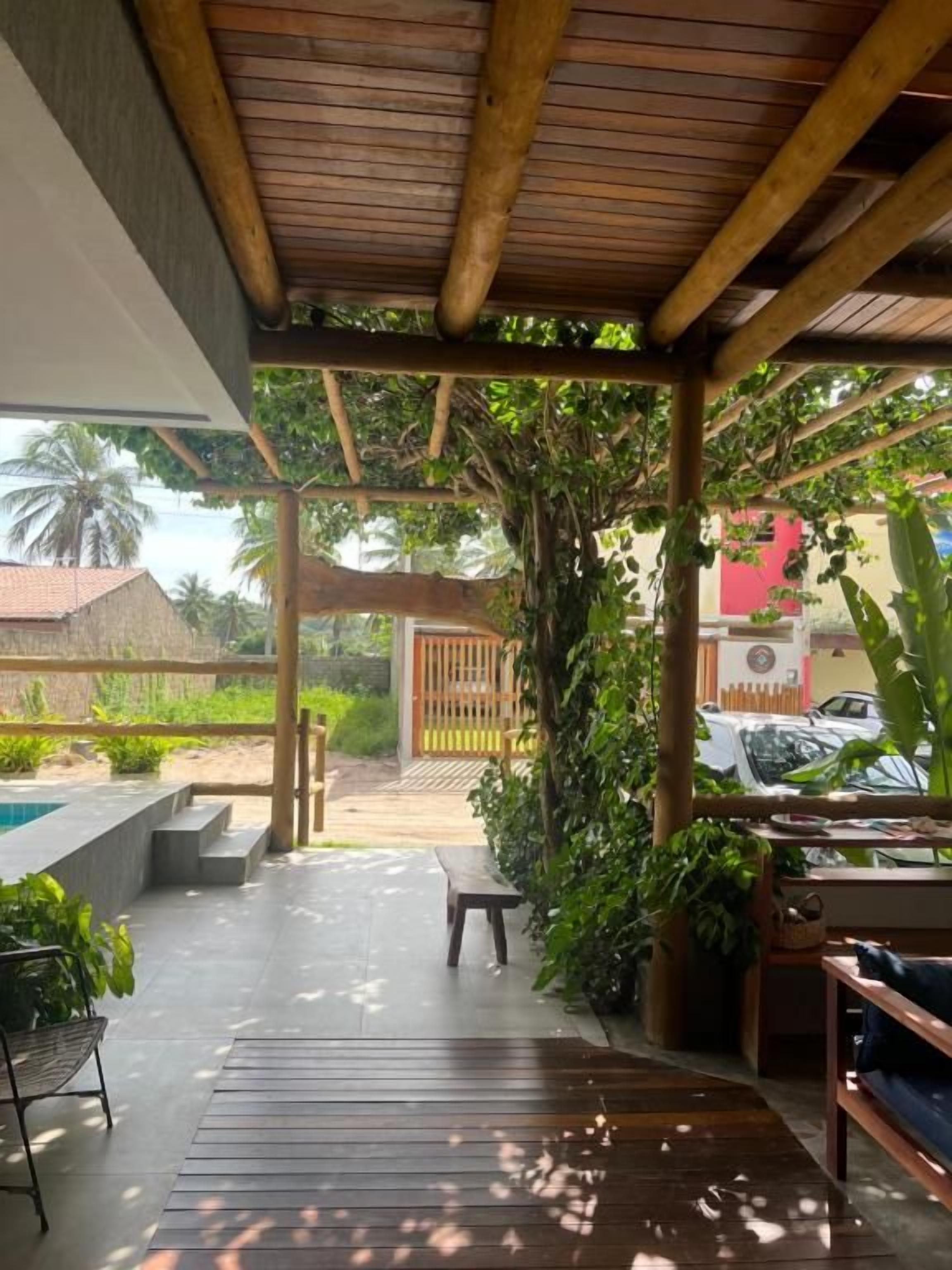 Espaço ao ar livre coberto com deck de madeira, assentos e vegetação exuberante.