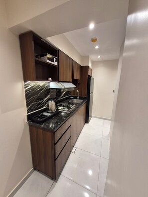 Cozinha moderna com armários de madeira escura, bancada de mármore preto e pia de aço inoxidável.