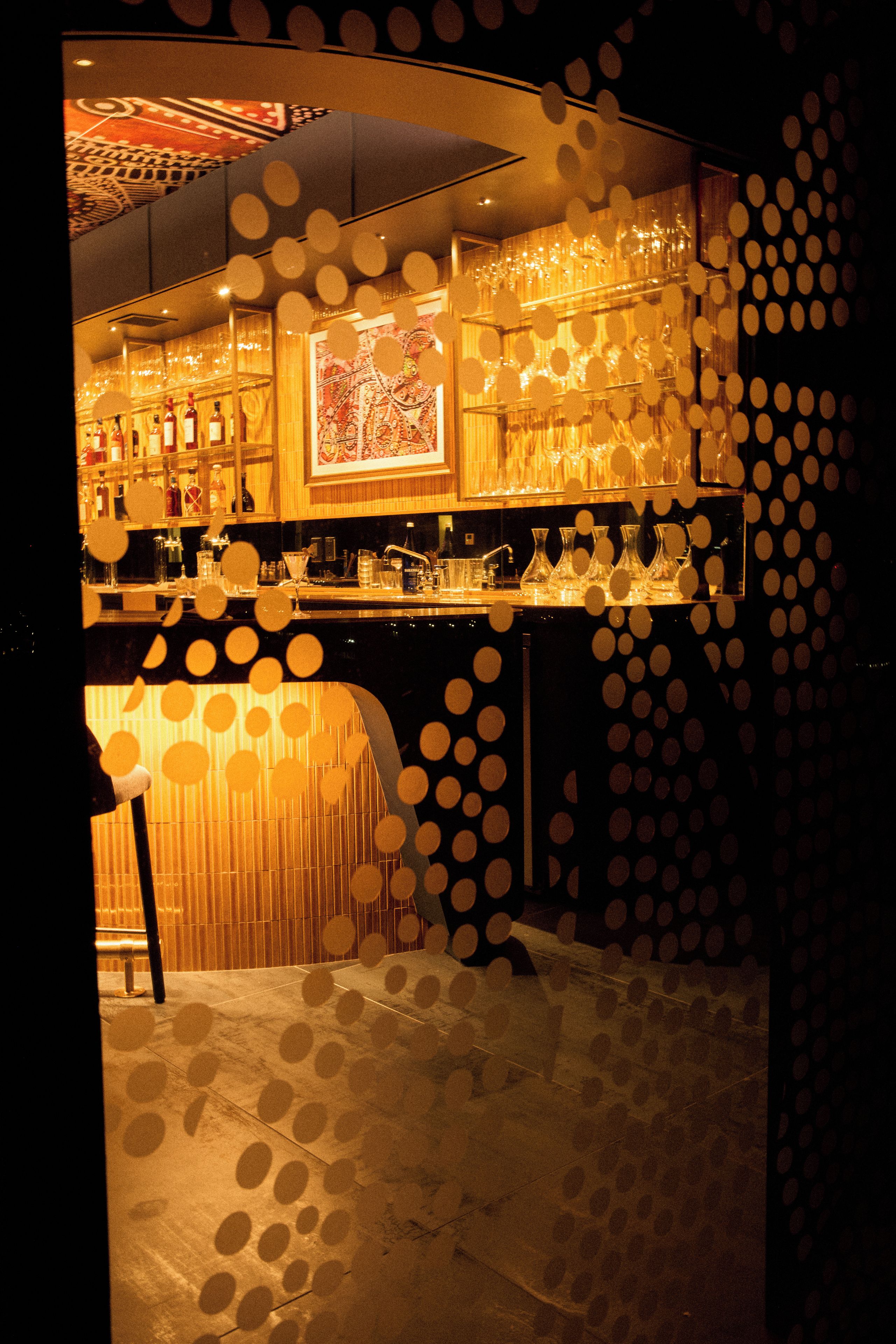 Uma área de bar com garrafas e copos, parede e piso estampados.