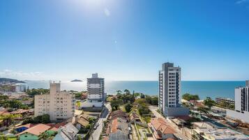 Paisagem costeira urbana com edifícios modernos, céu claro e vista para o mar.