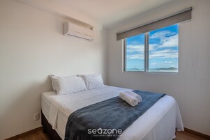 Quarto com cama, janela com vista e ar condicionado.