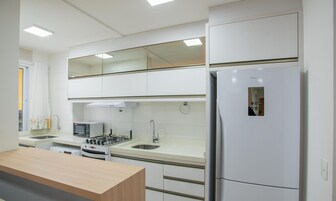 Uma cozinha moderna com micro-ondas, fogão, pia e geladeira embutidos.