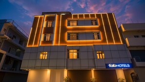 Um hotel moderno com um letreiro chamativo 'fabHOTELS', apresentando um design limpo e contemporâneo, com linhas iluminadas e telhado plano.