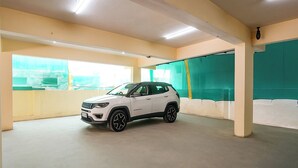 Um SUV branco estacionado em um espaço amplo e bem iluminado, com grandes janelas e uma divisória verde.