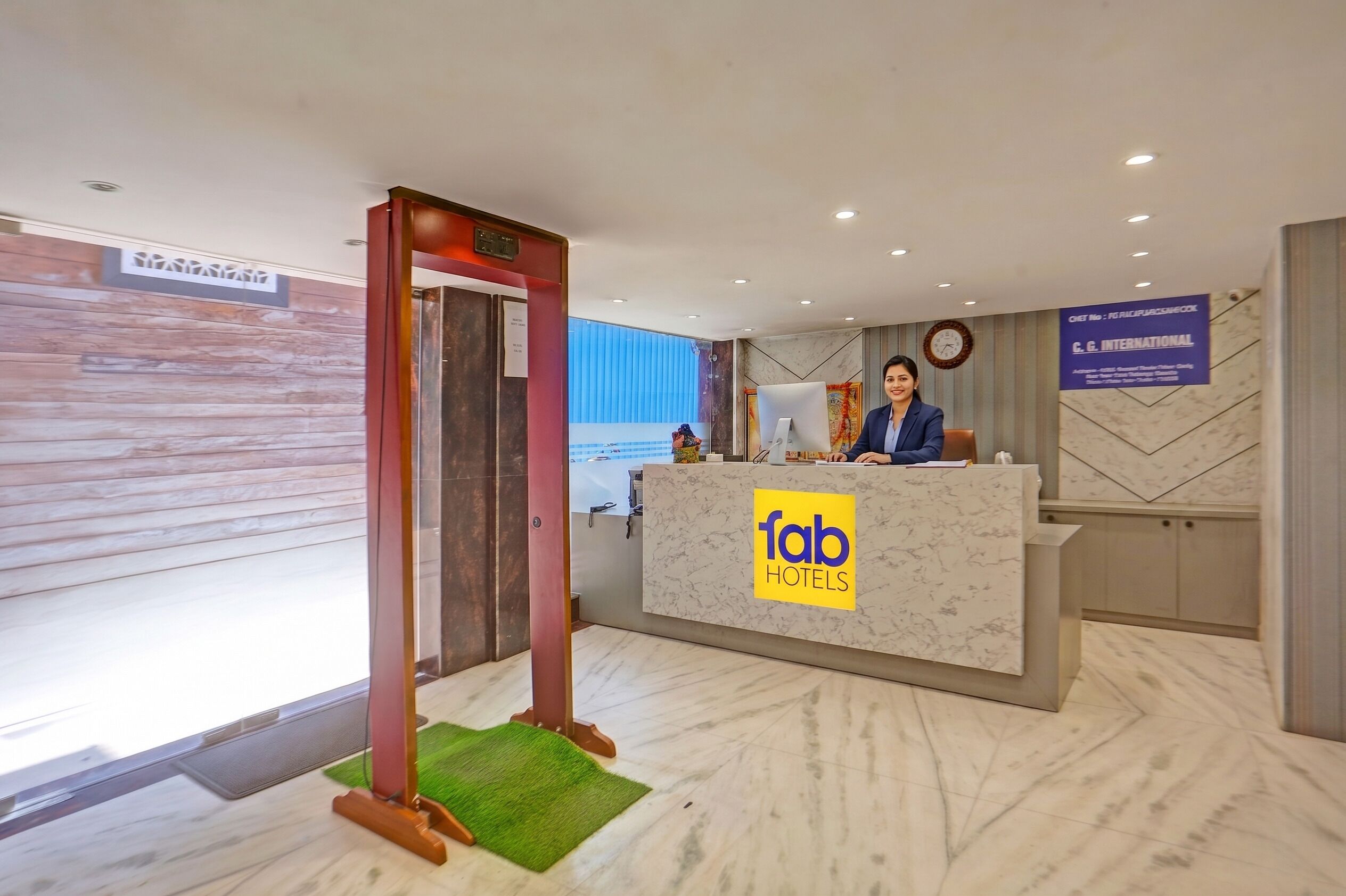 Uma receção de hotel com balcão de mármore, zona de receção e um relógio na parede.