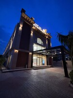 Um hotel moderno com entrada imponente, área externa coberta e fachada bem iluminada.