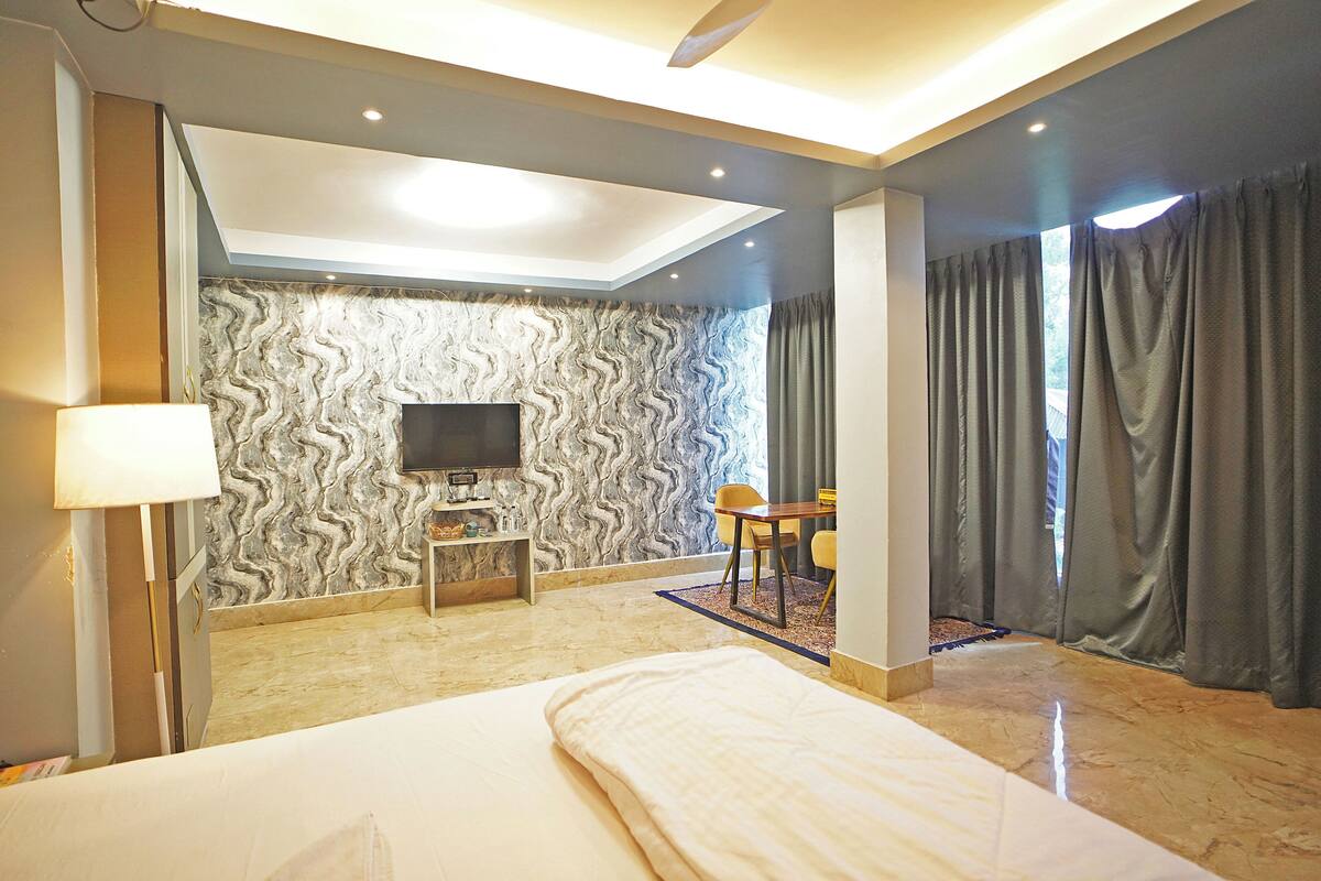 Quarto de hotel com cama, televisão, escrivaninha e cadeira.