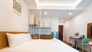 Quarto de hotel com uma cama grande, uma escrivaninha com duas cadeiras, uma cozinha compacta e uma escada.