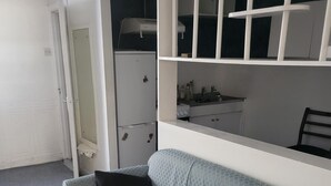 Quarto compacto com cozinha compacta, mini-geladeira e sofá.
