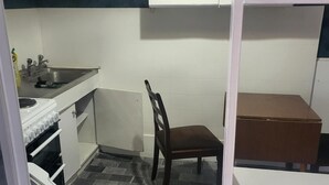 Cozinha compacta com pia, fogão e cadeira.
