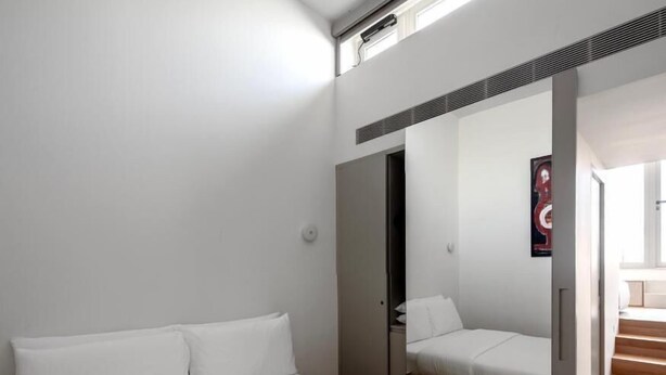 Quarto moderno com uma cama grande, um guarda-roupa e um espelho refletindo o ambiente.