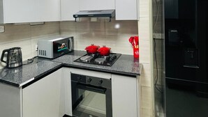 Cozinha moderna com micro-ondas, fogão e forno embutidos. Há uma cafeteira e uma panela vermelha no balcão.