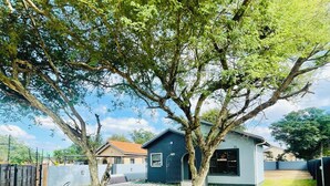 Uma casa com entrada pavimentada, um pequeno galpão e um gramado bem cuidado.