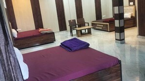 Quarto de hotel com duas camas, um sofá, uma mesa e uma cadeira.