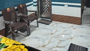 Um banheiro público com paredes de madeira, piso de azulejo, televisão fixada na parede e algumas cadeiras de madeira.