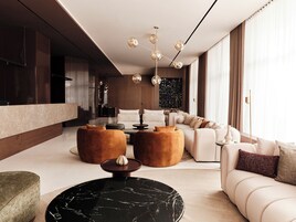 Uma sala de estar moderna com uma mesa de centro de mármore, pufes de couro, um conjunto de sofás e um lustre.