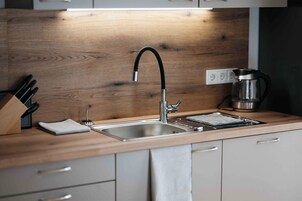 Uma cozinha moderna com bancada de madeira, pia de aço inoxidável e máquina de café.