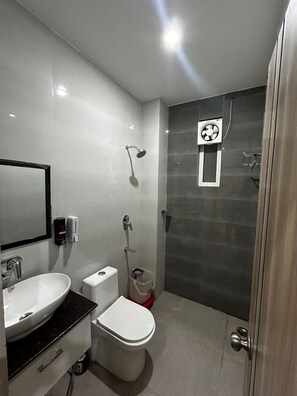 Uma casa de banho moderna com lavatório, sanita e chuveiro.
