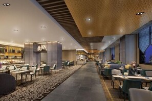 Um saguão de hotel com um corredor longo, áreas de estar e um bar.